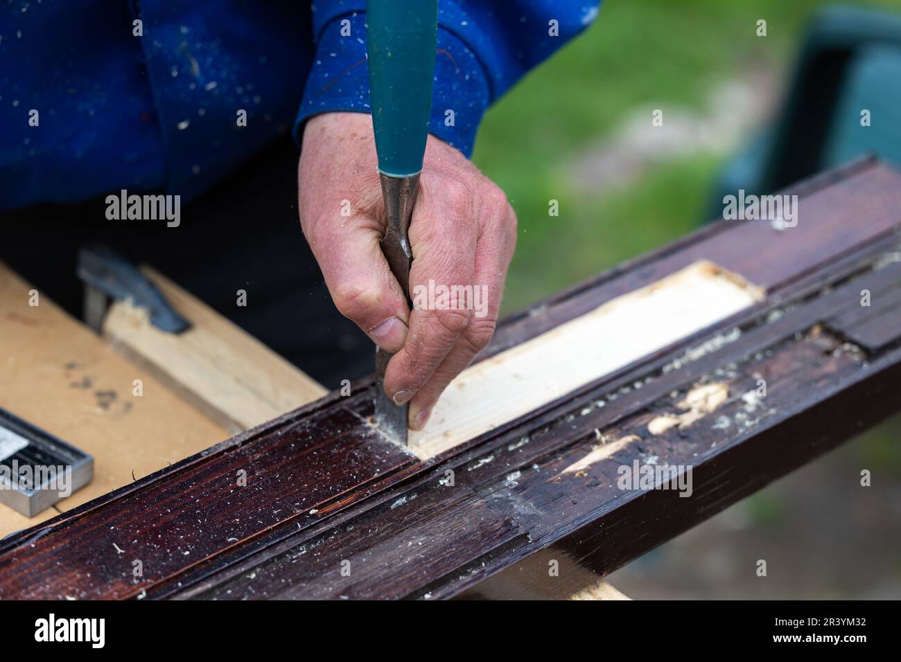 Hands of a man processing wooden elements with a chisel. Professional ...