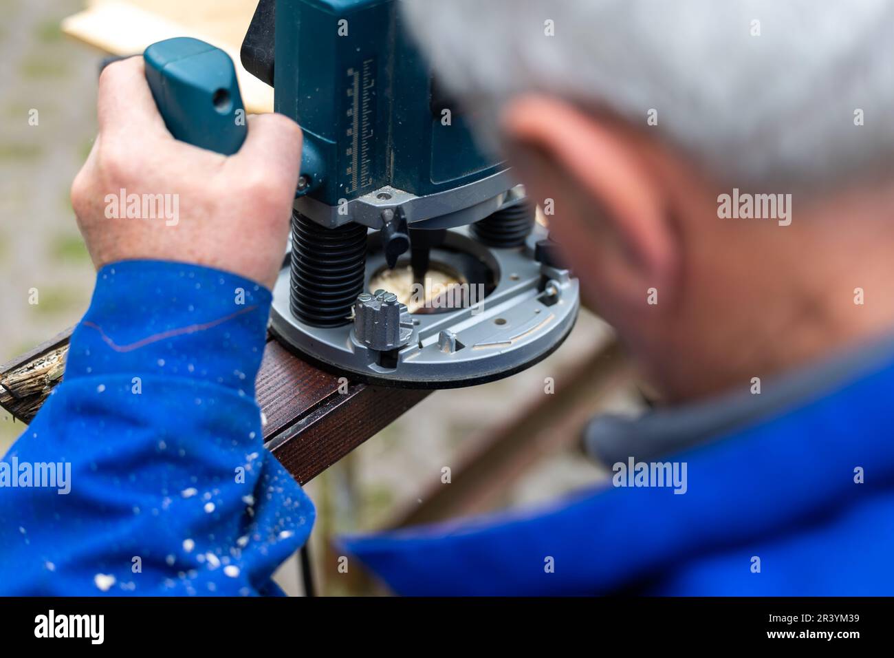 A man processing wooden elements with an electric milling machine ...