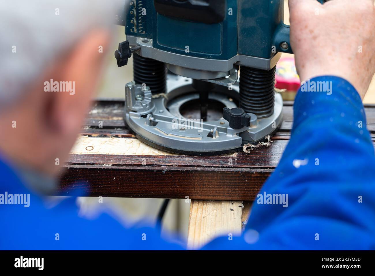 A man processing wooden elements with an electric milling machine ...