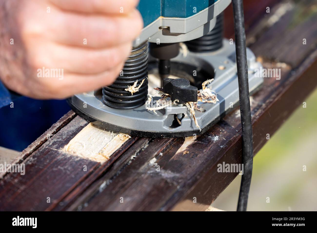 A man processing wooden elements with an electric milling machine ...