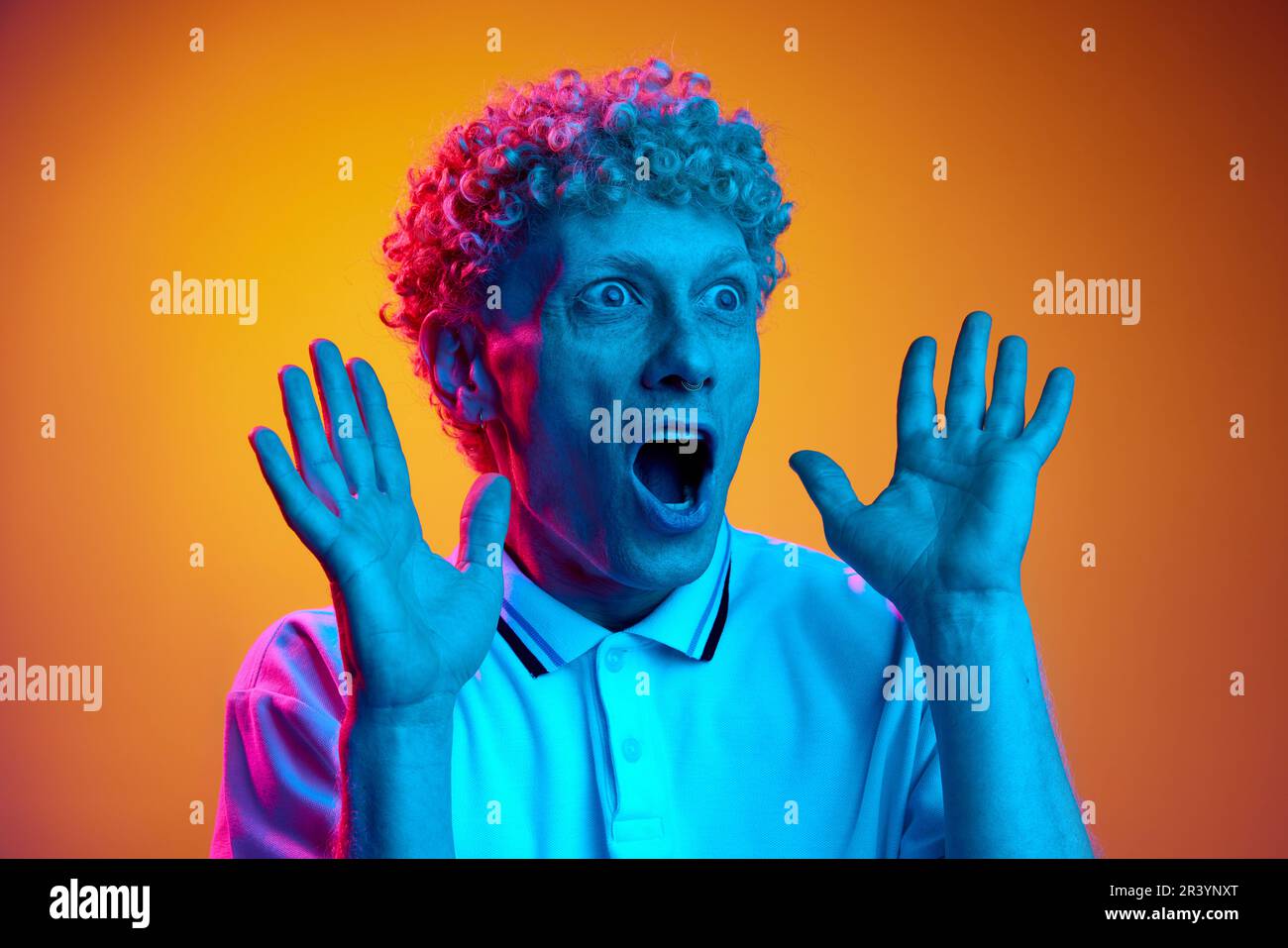 Shock. Portrait of mature man with curly hair spreading hands in ...