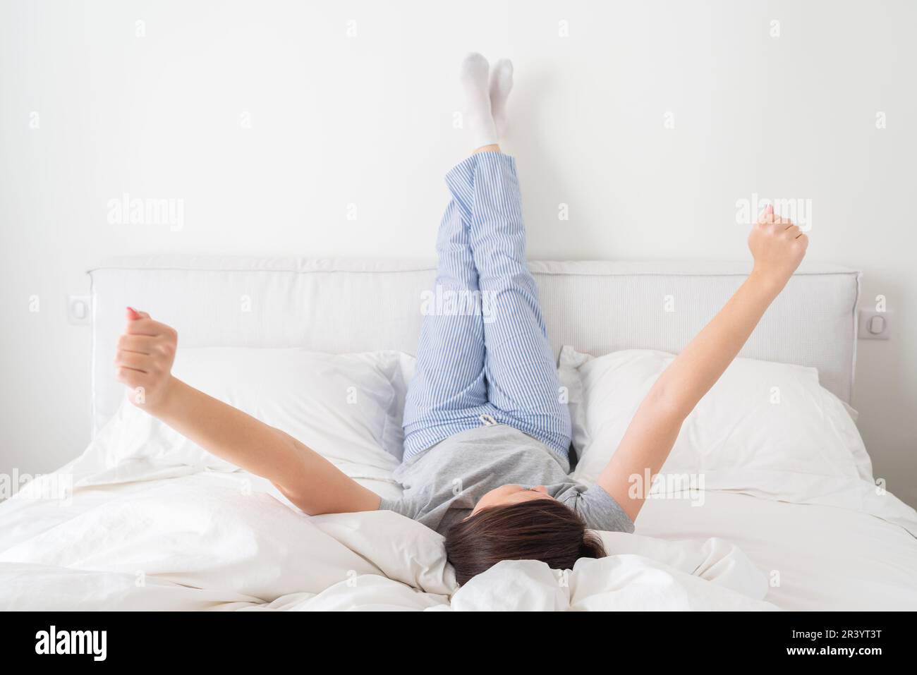Woman lying in bed with legs raised up against a wall Stock Photo - Alamy