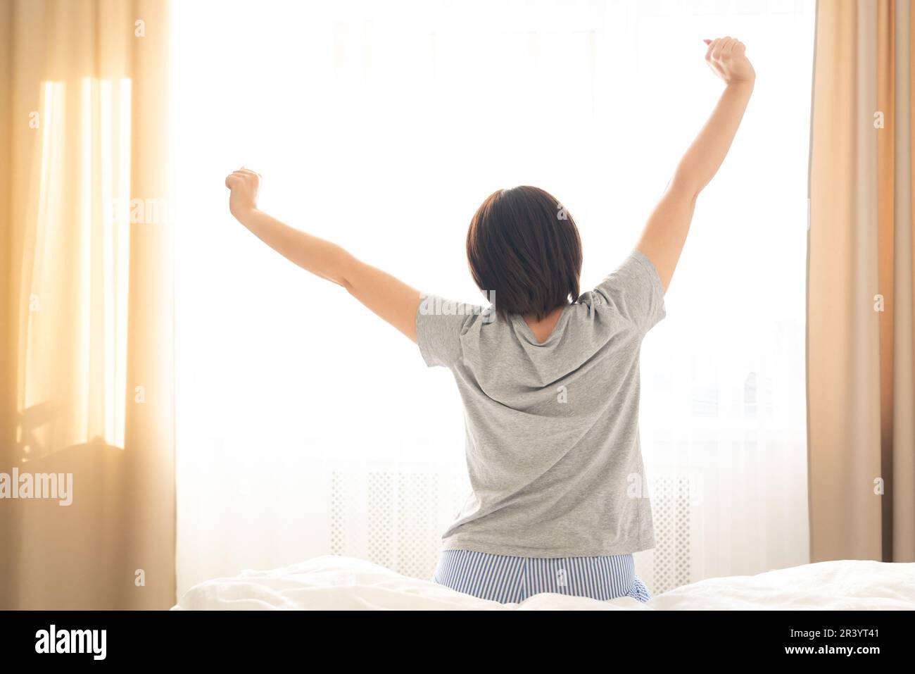 Woman stretching in bed after wake up, back view Stock Photo - Alamy