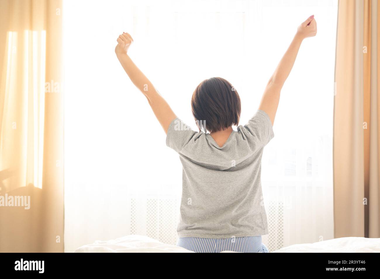 Girl stretching in bed after wake up, back view Stock Photo - Alamy