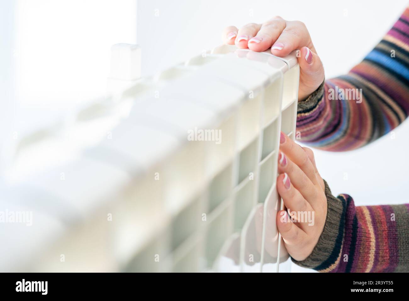 Woman touching warm radiator with both hands Stock Photo - Alamy