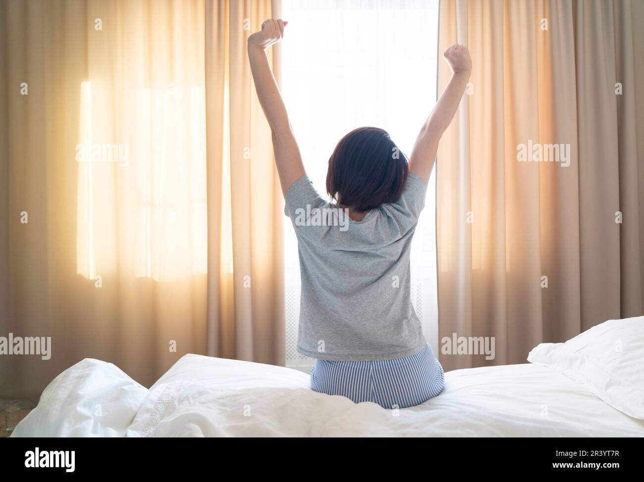Back view of woman stretching in bed after waking up Stock Photo - Alamy