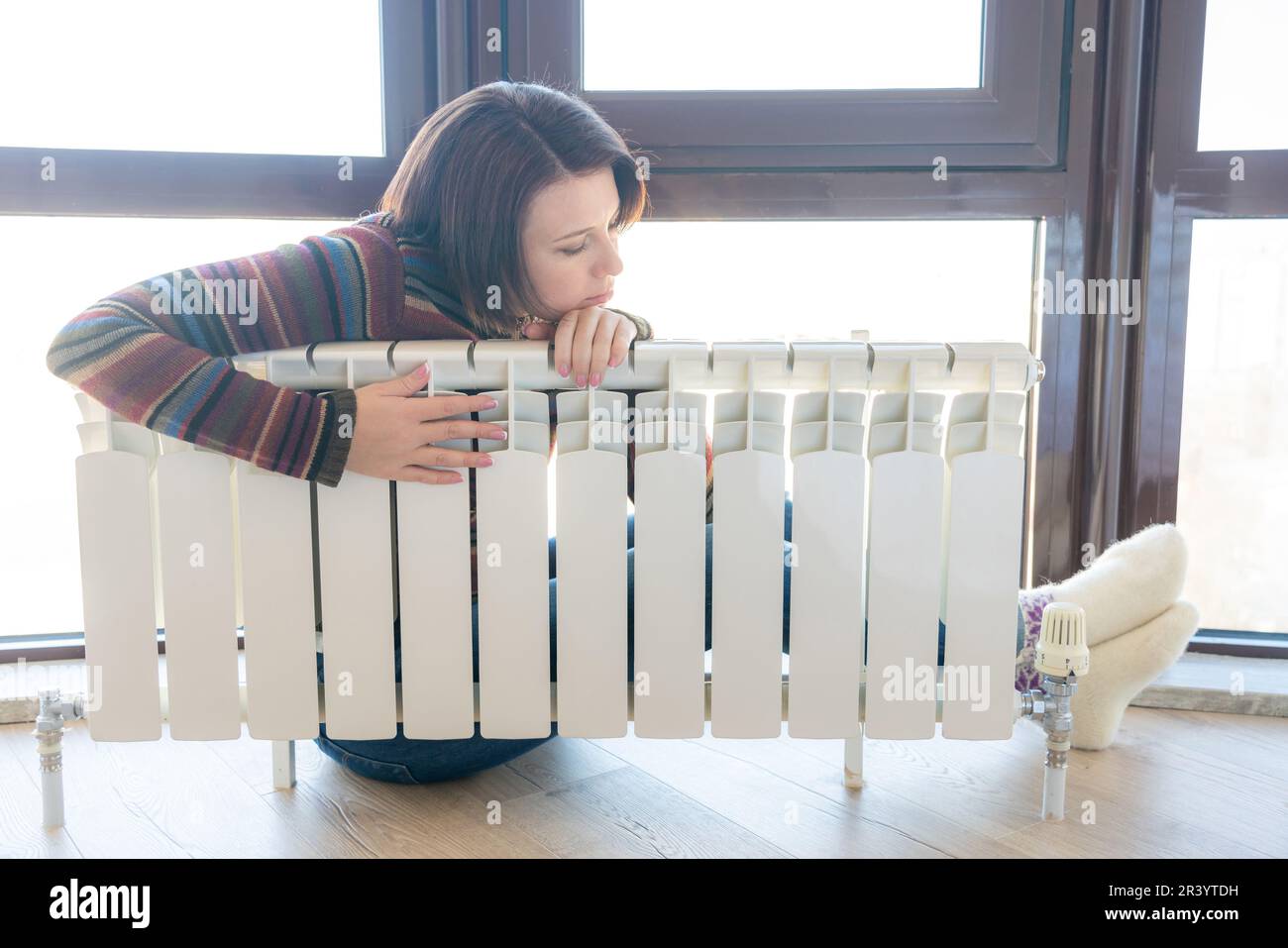 Woman wearing pullover sitting near heater radiator and hugs it Stock ...