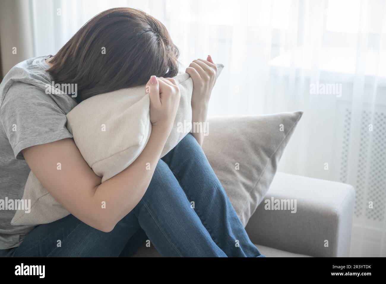 Sad girl sitting on couch and hugging a pillow, loneliness and sadness ...