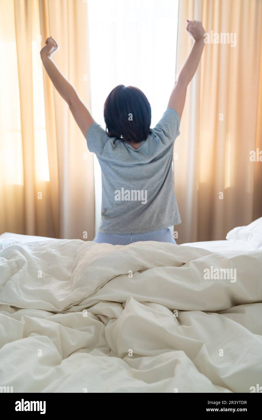 Woman stretching in bed after wake up, back view Stock Photo - Alamy