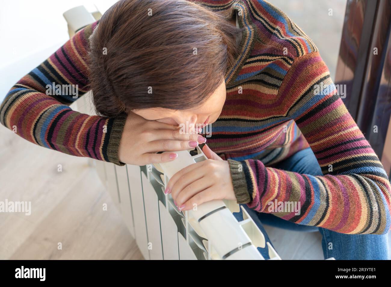 Woman wearing pullover sitting near heater radiator and hugs it Stock ...