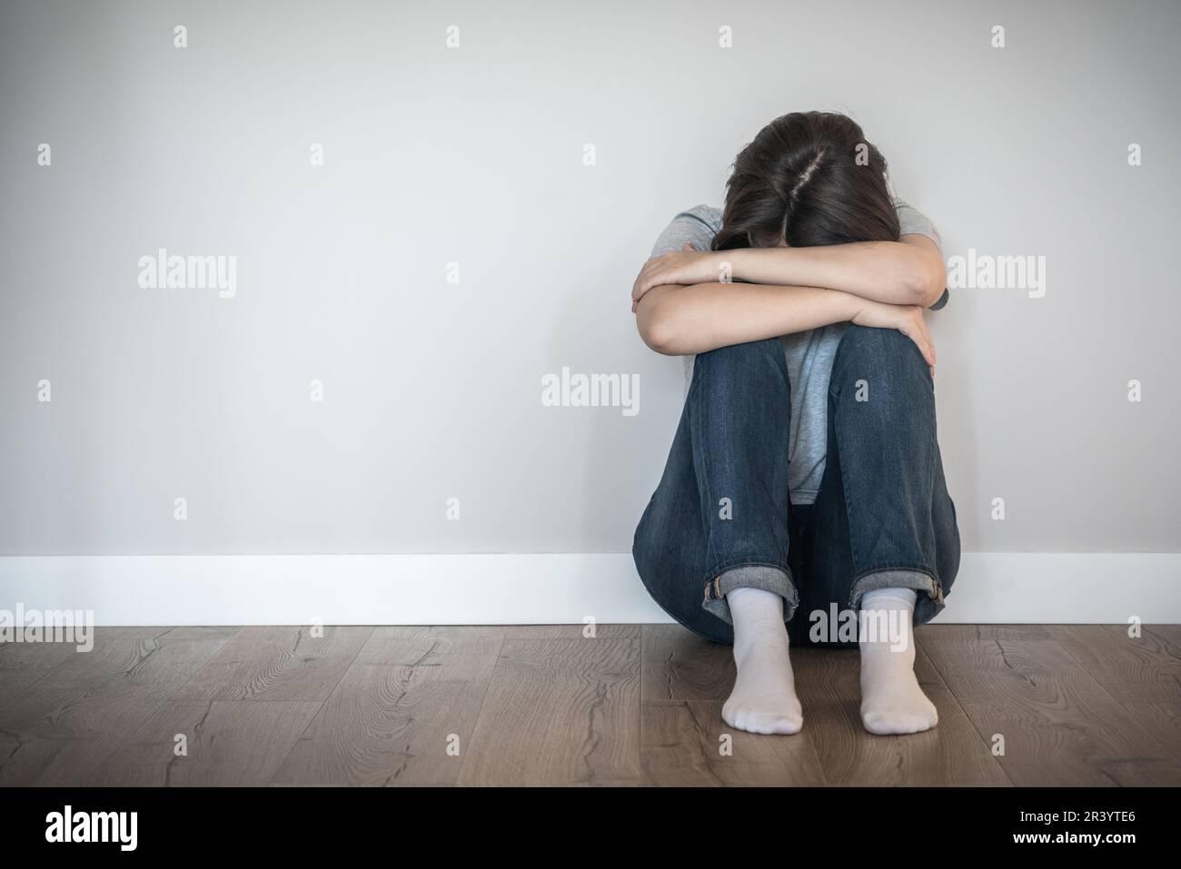 Sad woman sitting on a floor alone in empty room, despair and lonely ...