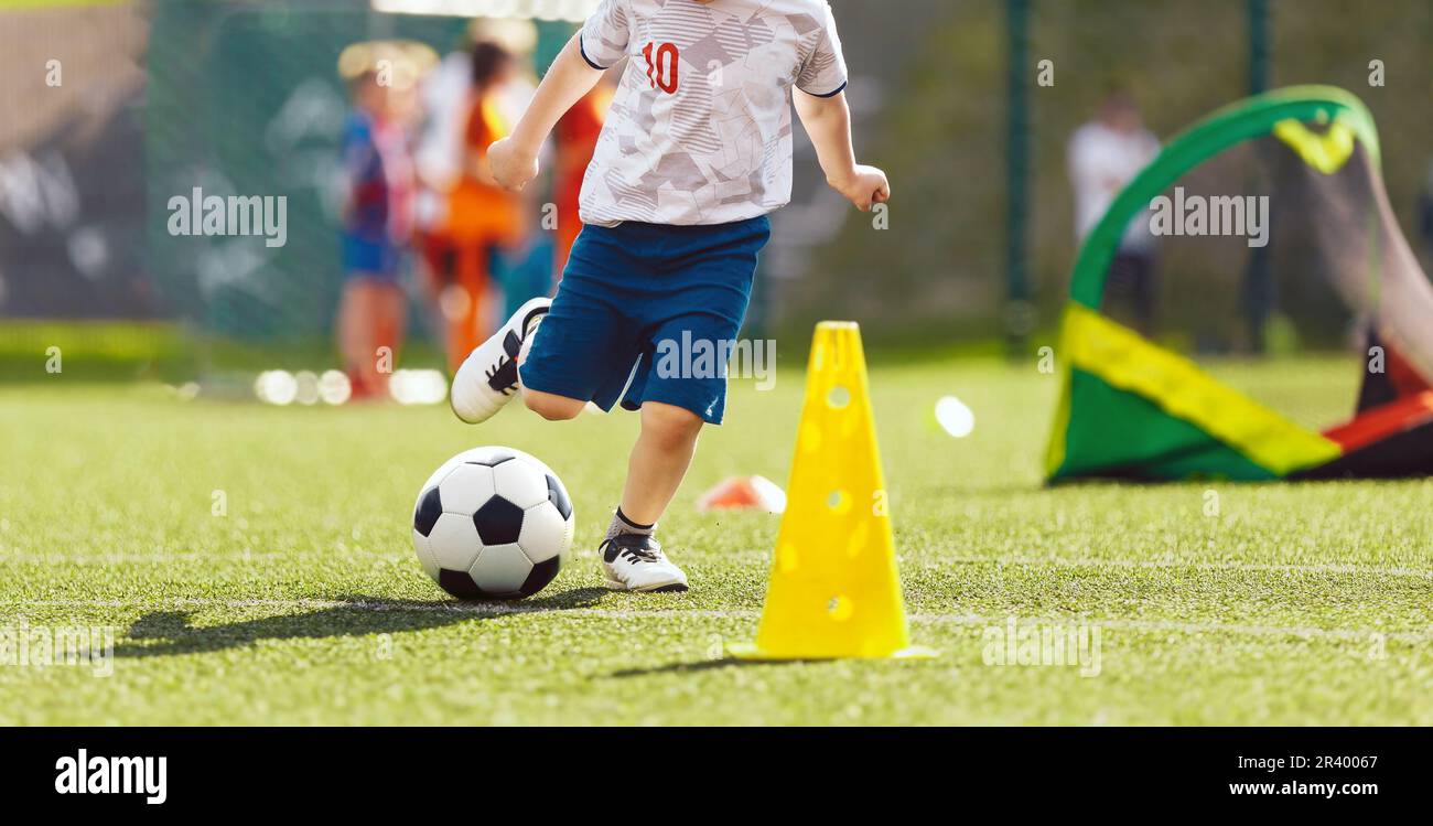 Little chlld running and kicking a soccer ball. Legs of young football ...