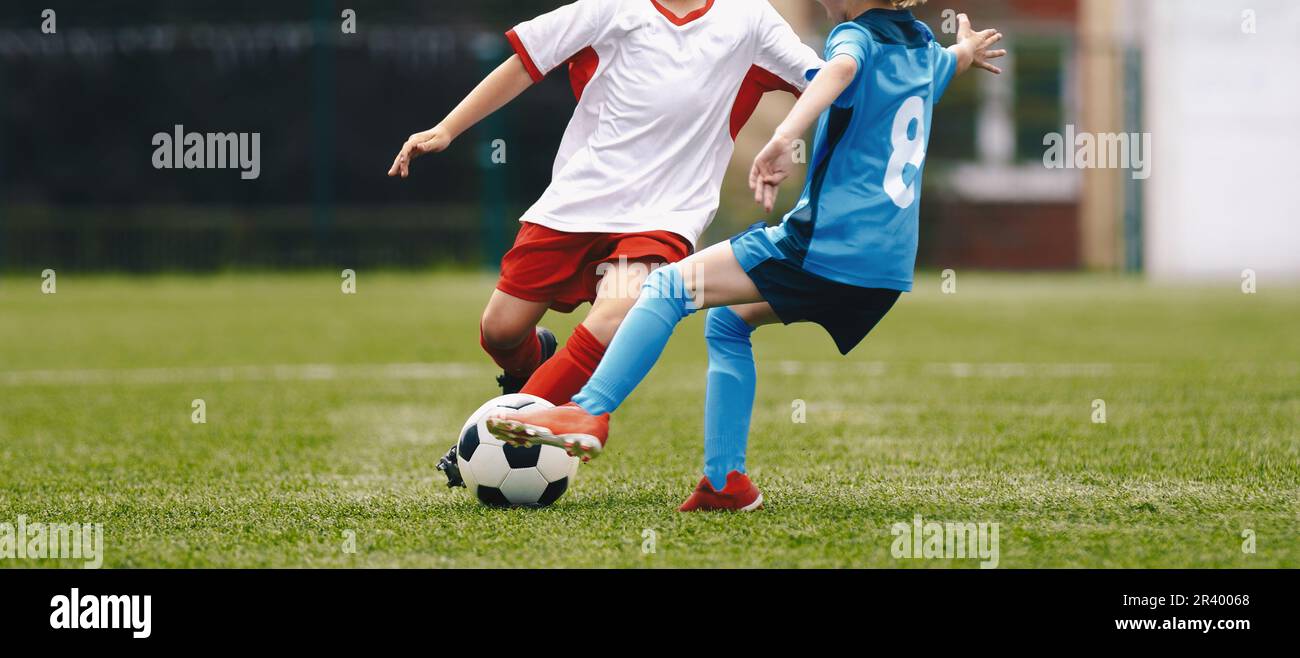 Two soccer players running and kicking a soccer ball. Legs of two young ...