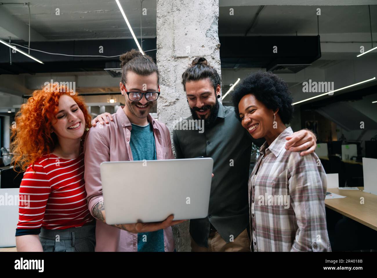 Diverse group of professionals meeting in office. IT programmers use computer, talk strategy ...