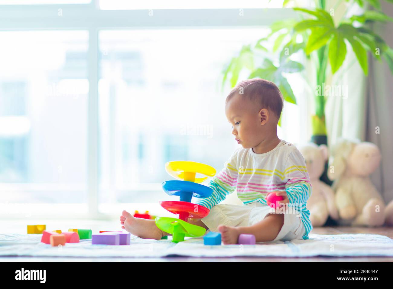 Adorable Asian baby boy learning to crawl and playing with colorful ...