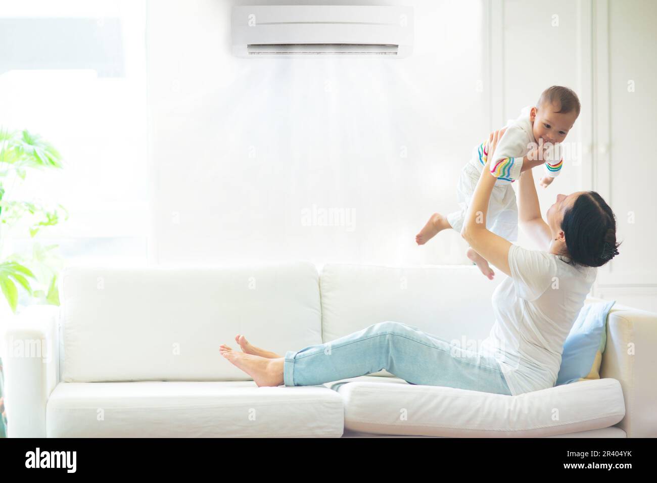 Asian mother and child with air conditioner remote control. Comfortable ...