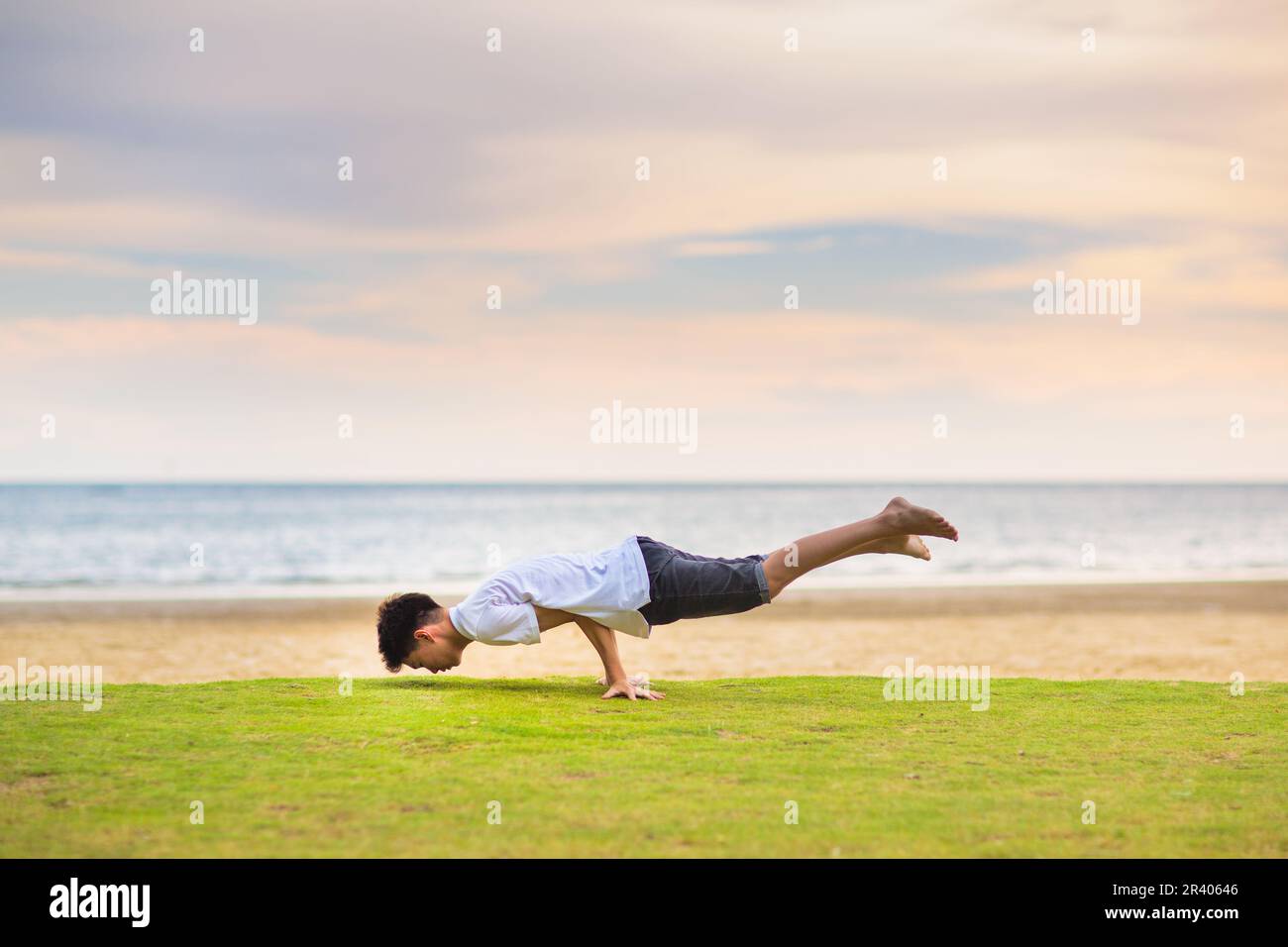 Teenager doing calisthenics exercise. Beach yoga at sunset. Teen boy ...