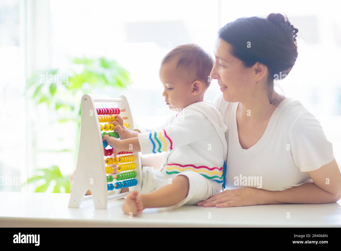 Baby boy and mother playing with wooden abacus. Kids learn to count ...