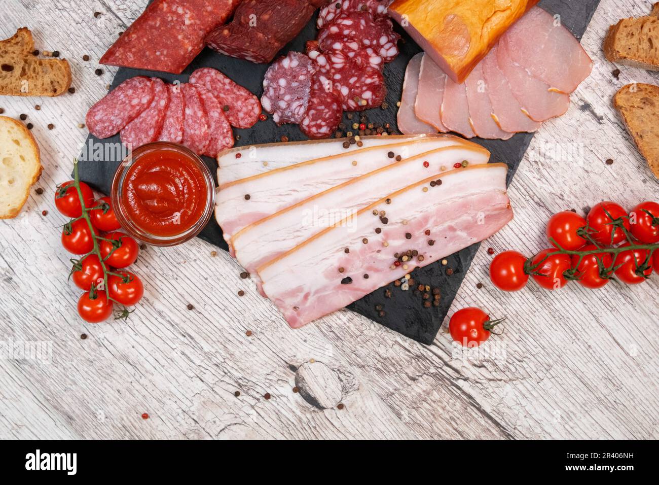 Antipasti different types of sausages and lard on a graphite board .Top ...