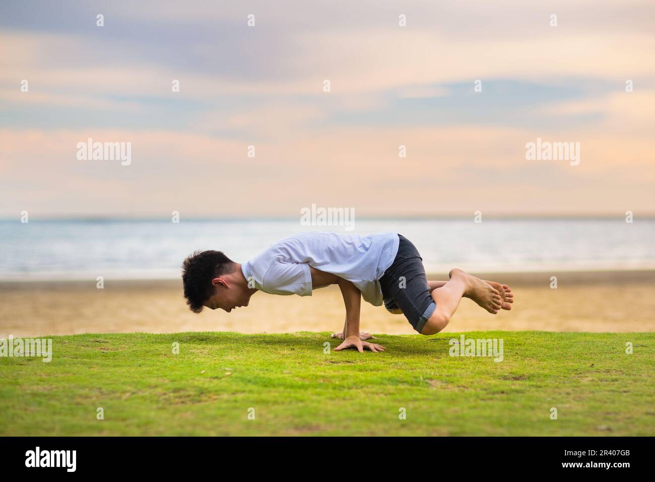 Teenager doing calisthenics exercise. Beach yoga at sunset. Teen boy ...