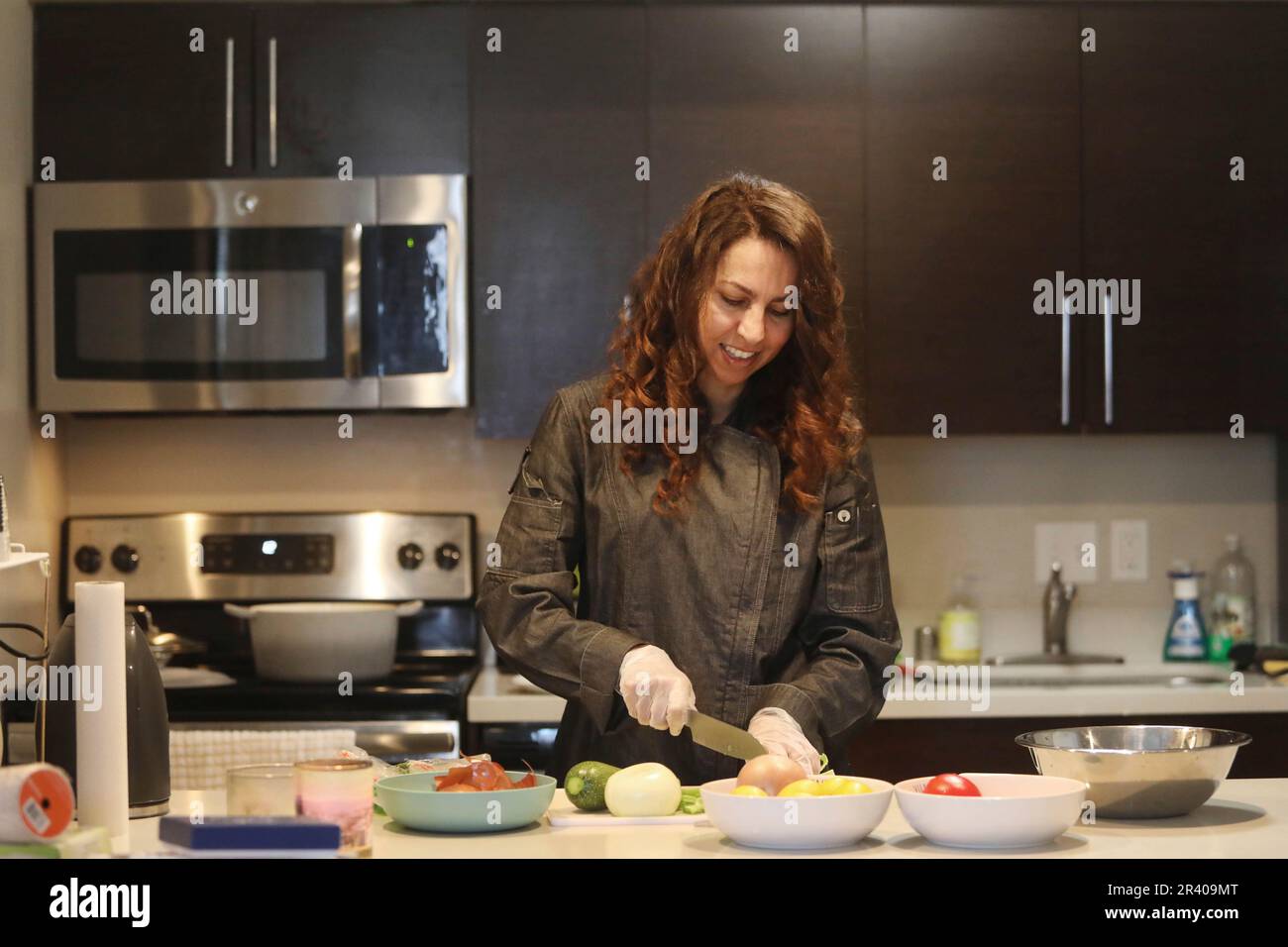 Shereen Hassan-Aly cuts vegetables as she prepares soup in a space she ...