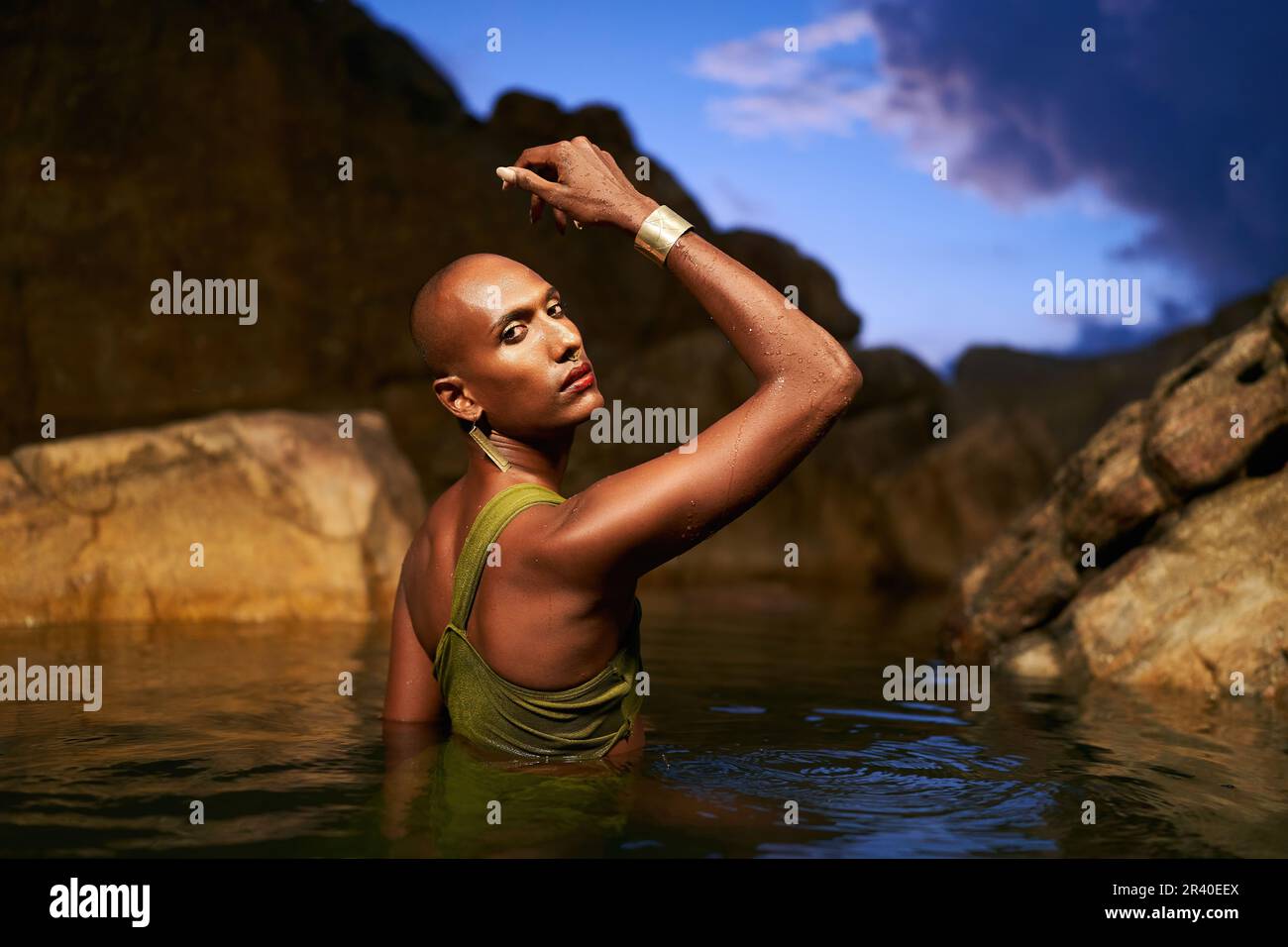 Non-binary person of color poses in water, shows jewelry inside scenic ...