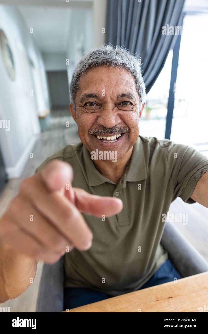 Close-up portrait of cheerful biracial senior man pointing at camera ...