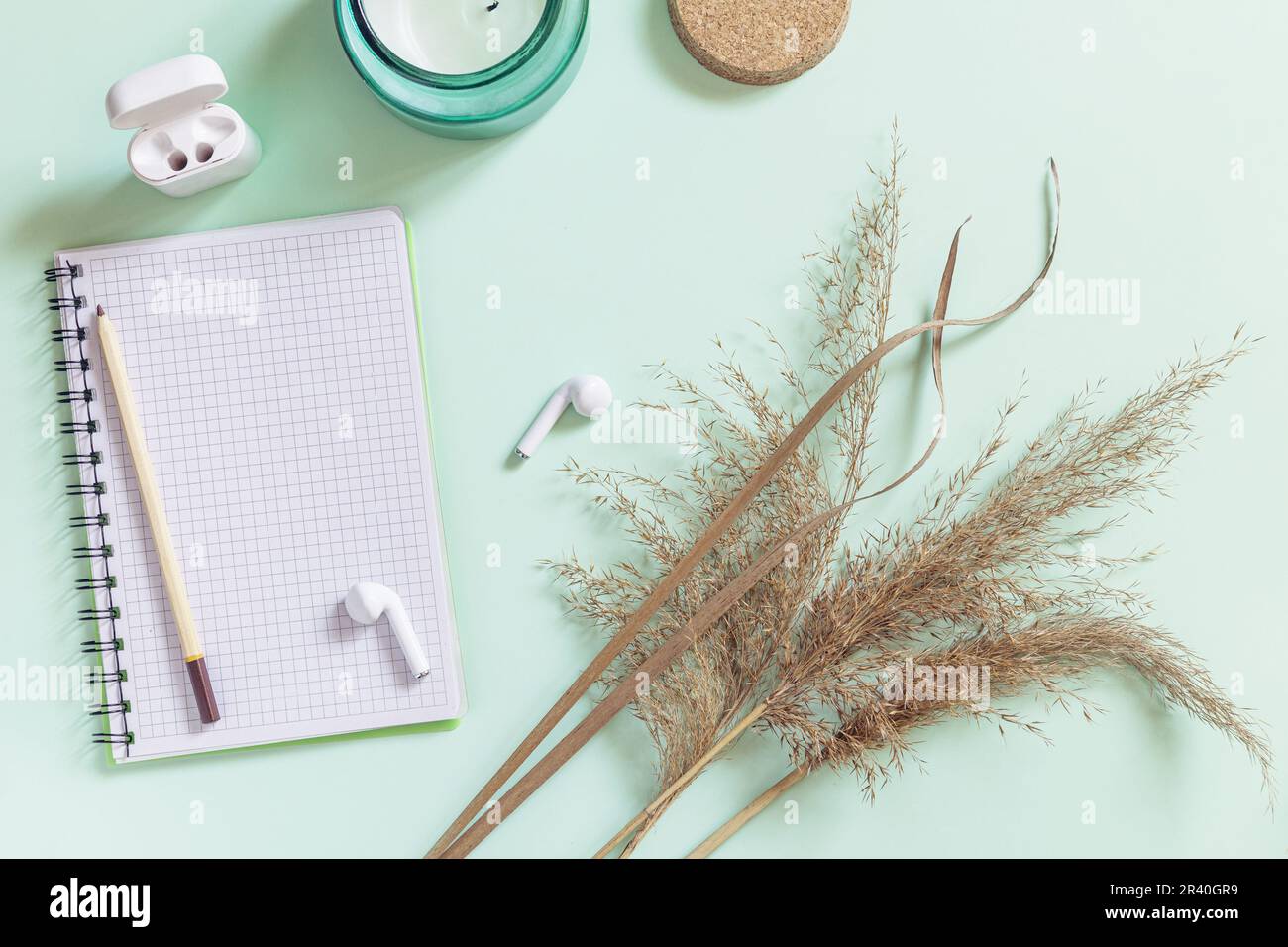 Flat lay still life aroma candle, pampas grass, notepad and pencil on a ...