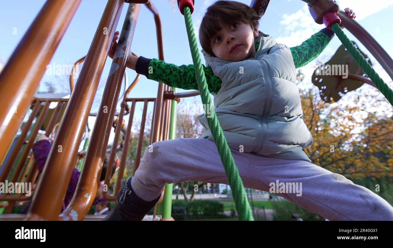 Little boy exercising outside holding in metal bar at playground ...