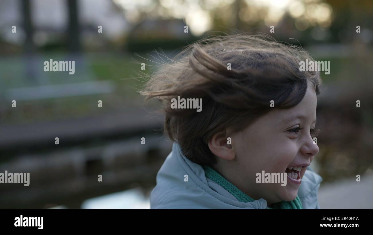 One active little boy runs outside in slow motion in handheld ...