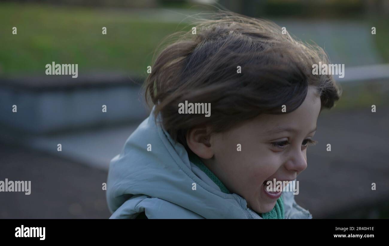 One active little boy runs outside in slow motion in handheld ...