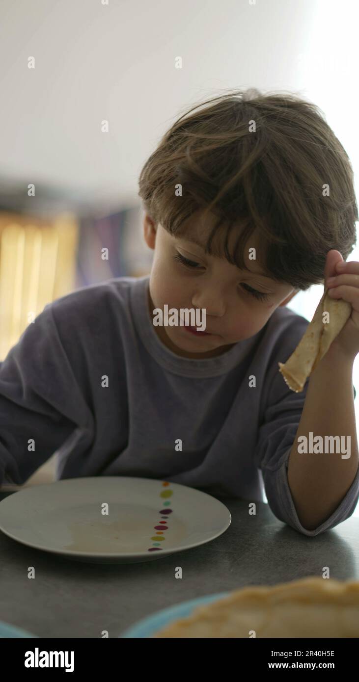 One little boy eating pancake in the morning wearing pajamas. Joyful ...