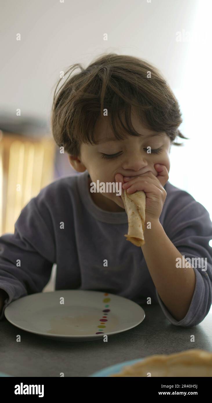 One little boy eating pancake in the morning wearing pajamas. Joyful ...