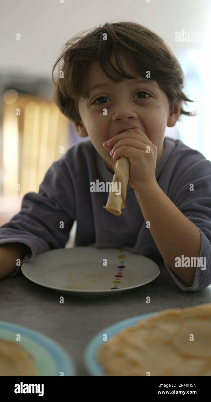 One little boy eating pancake in the morning wearing pajamas. Joyful ...