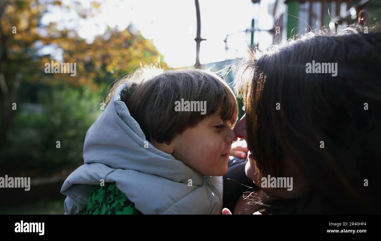 Happy mother and child doing eskimo kiss with nose standing outdoors ...