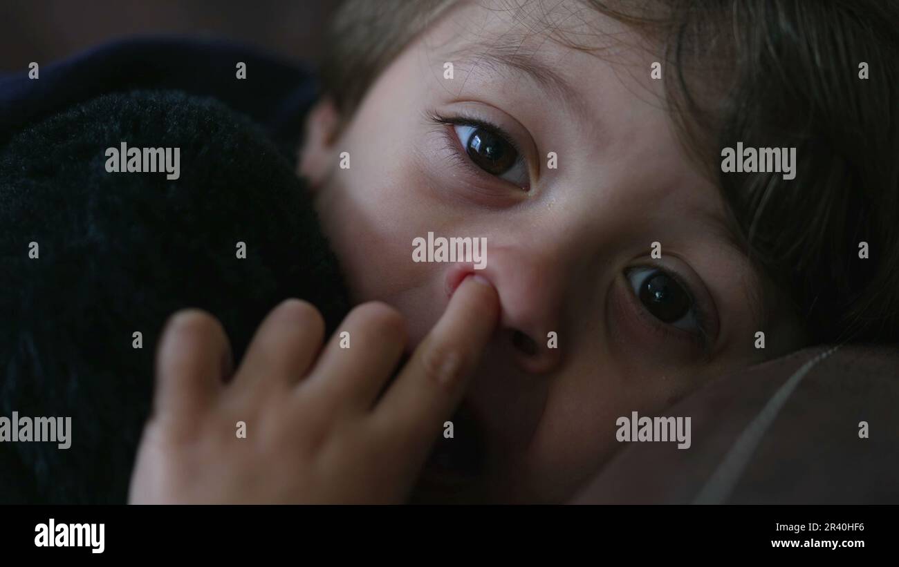 Child nose picking close up face with finger. One thoughtful little boy ...