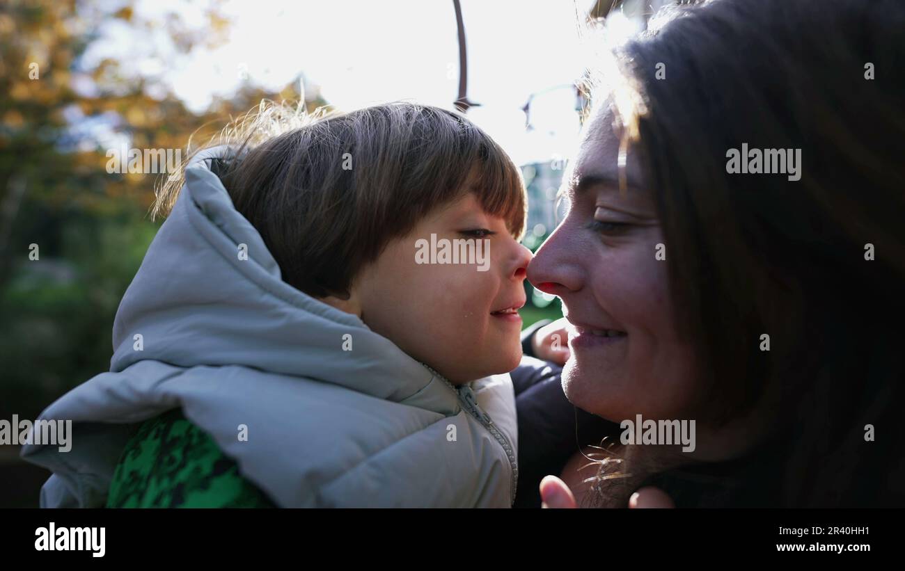 Happy mother and child doing eskimo kiss with nose standing outdoors ...