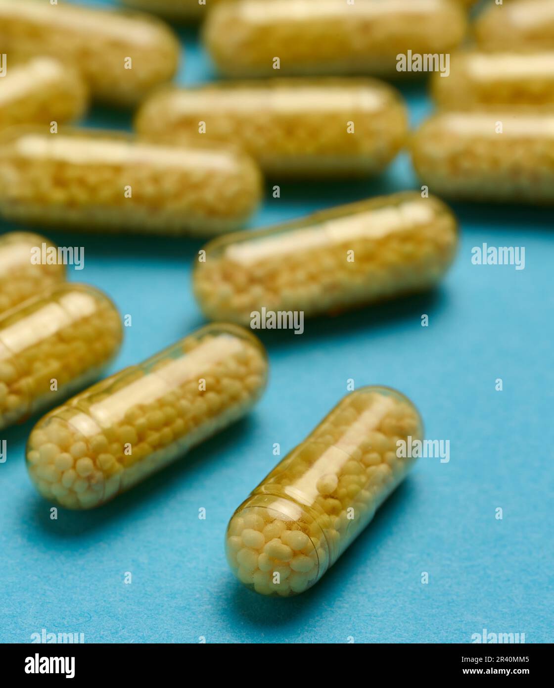 Transparent medical capsules with yellow granules inside on a blue ...
