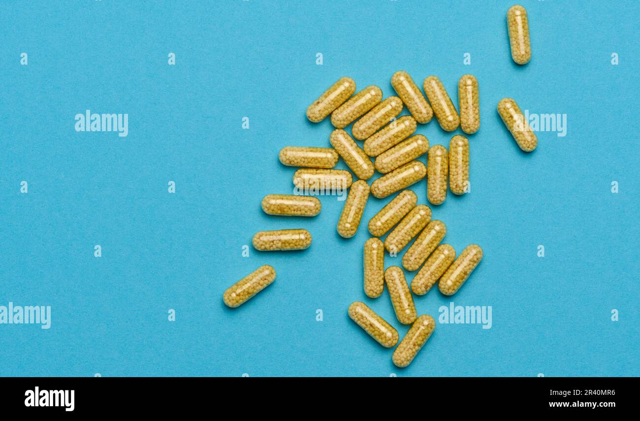 Transparent medical capsules with yellow granules inside on a blue ...
