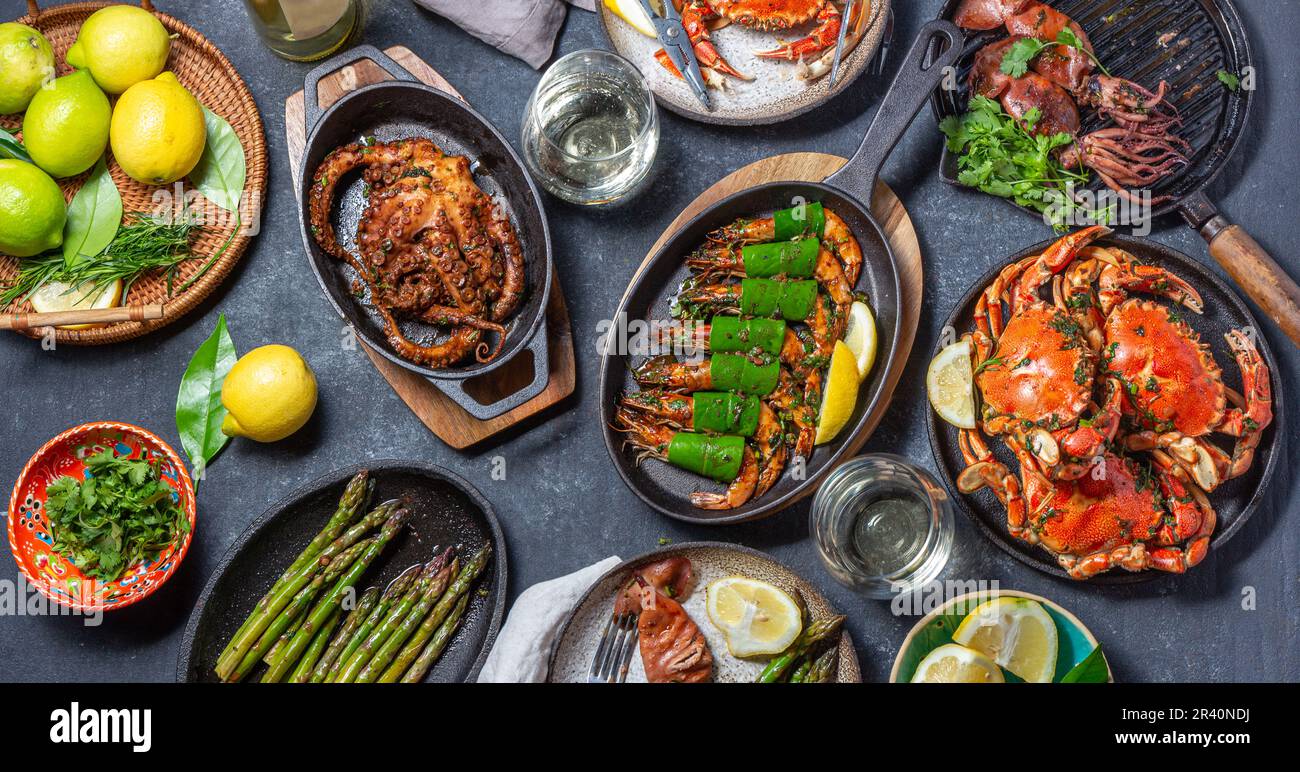 Set table with seafood dishes - cooked crabs, tiger shrimps, grilled ...