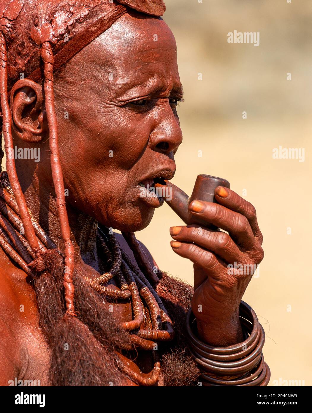 Portrait of an old woman of the Himba tribe with a smoking pipe in her ...
