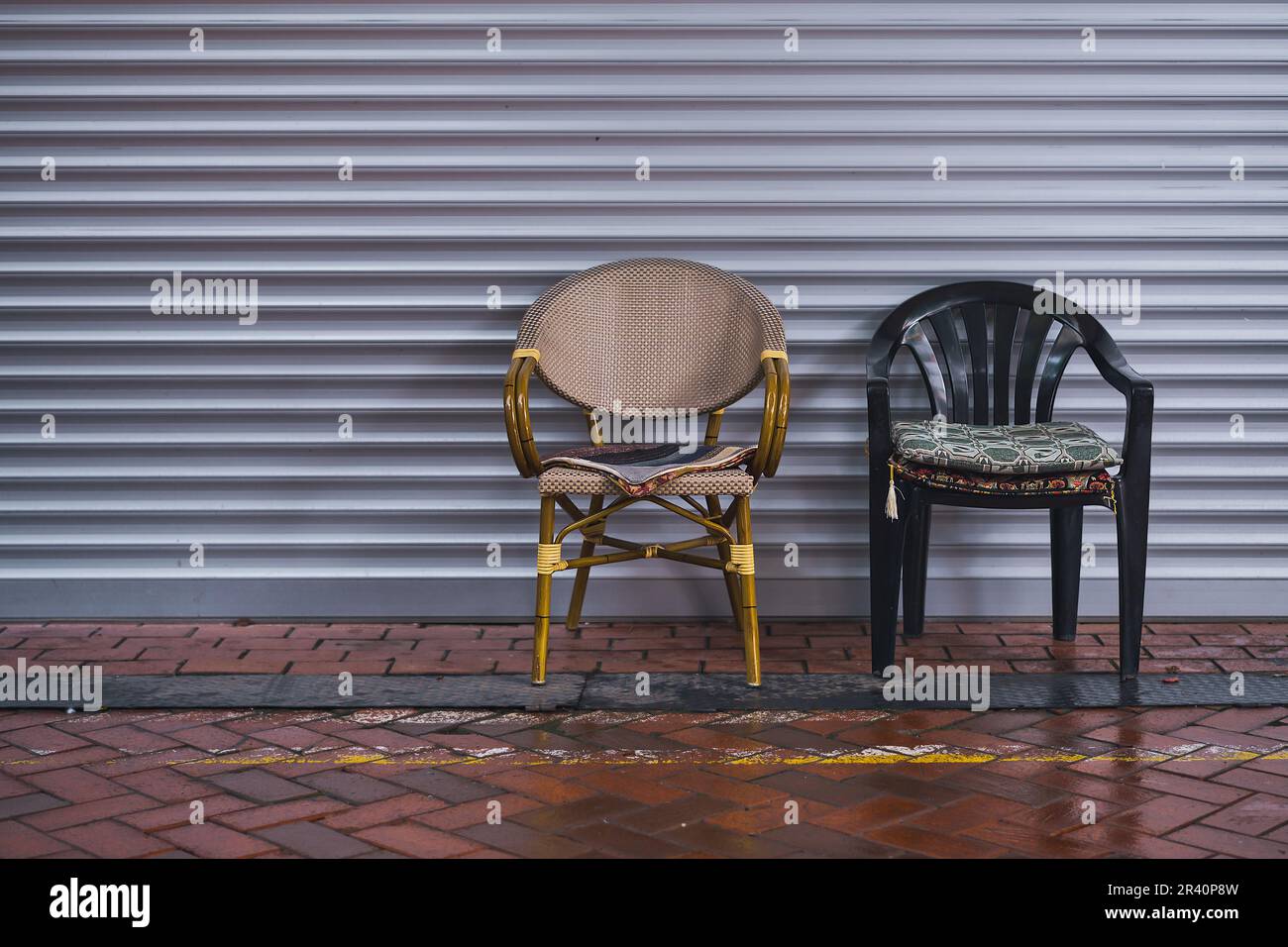 Chairs on the street near a roller-shuttered cafe, copy space. Street ...