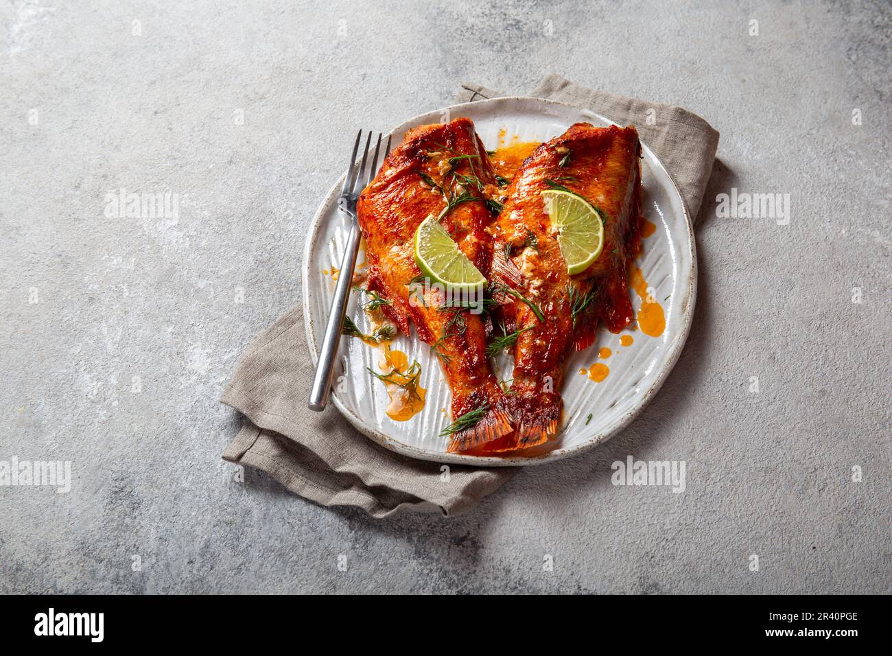Baked red sea bass on kraft white plate, concrete background Stock ...