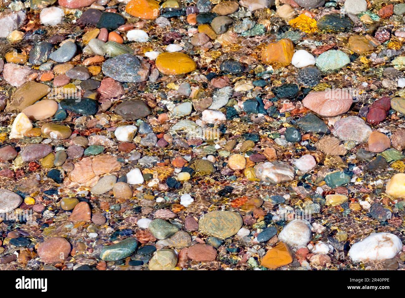 Close up abstract of a shallow stream flowing over a multitude of wet ...