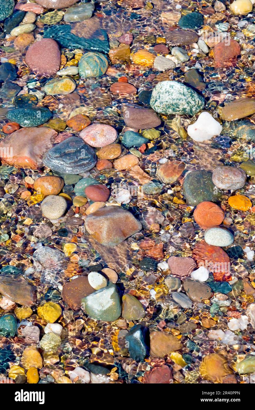 Close up abstract of a shallow stream flowing over a multitude of wet ...