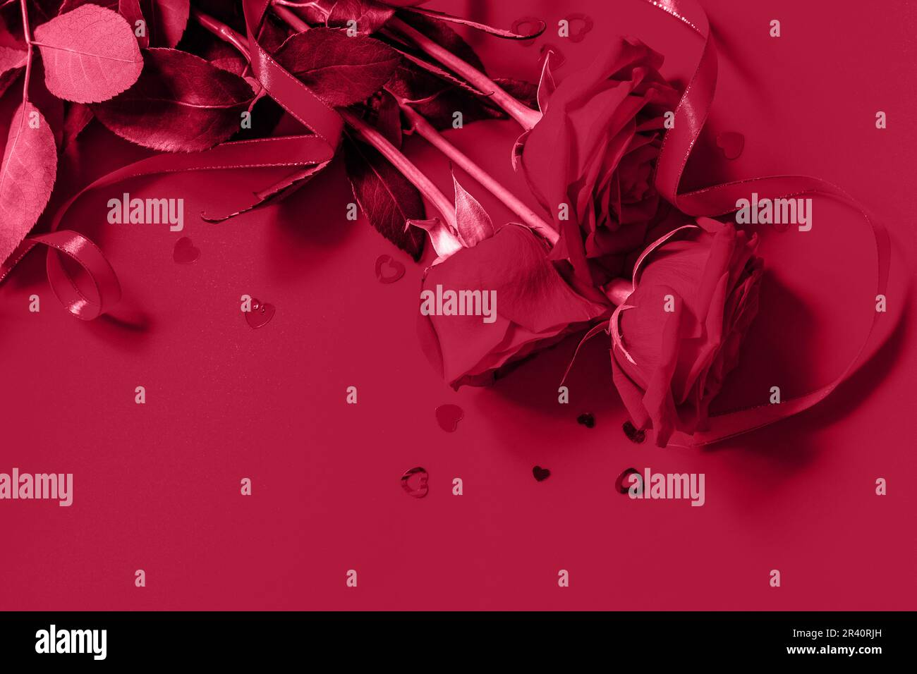 Red roses and heart shaped decor on a red background. Copy space for ...