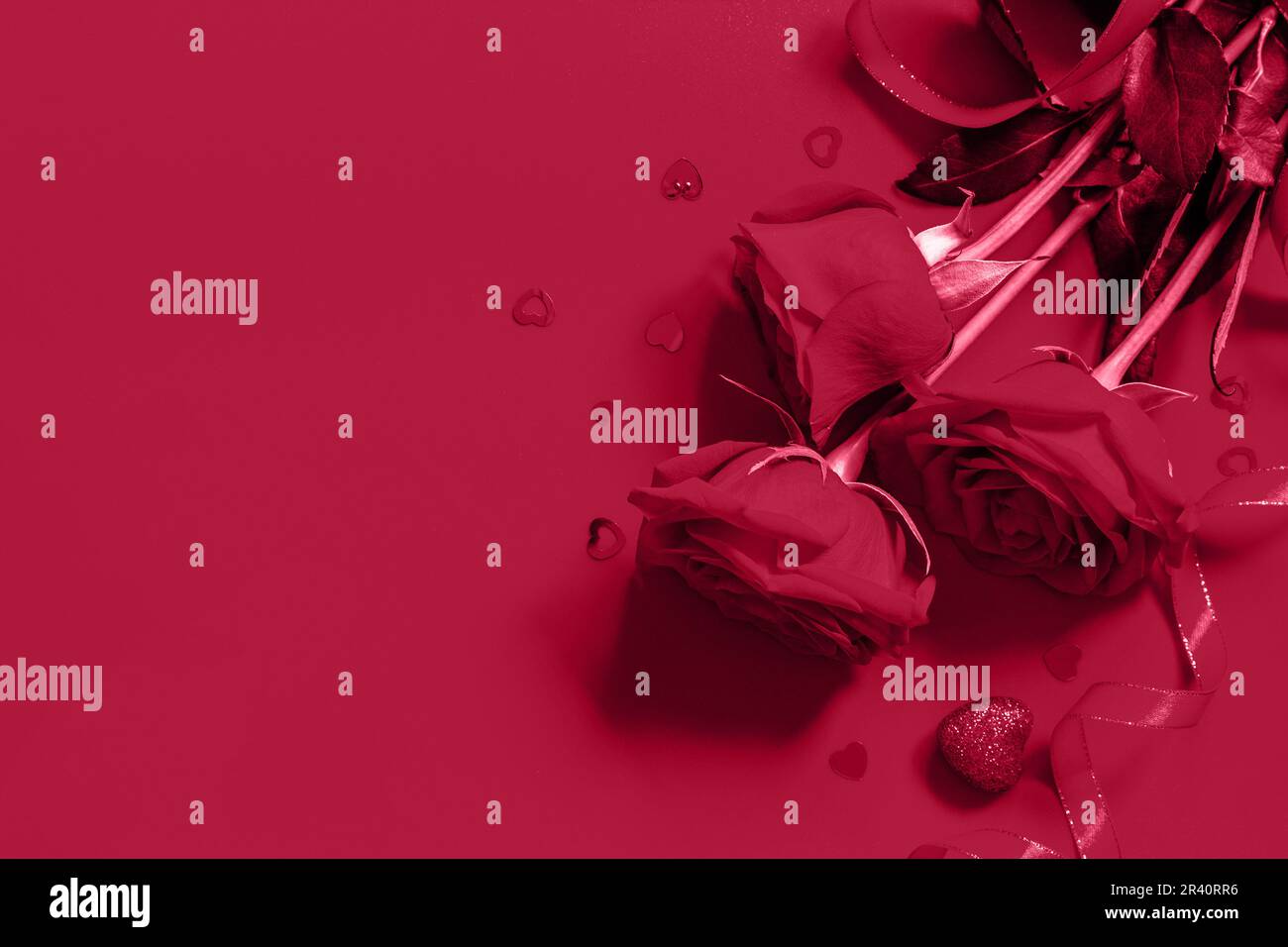 Red roses and heart shaped decor on a red background. Copy space for ...