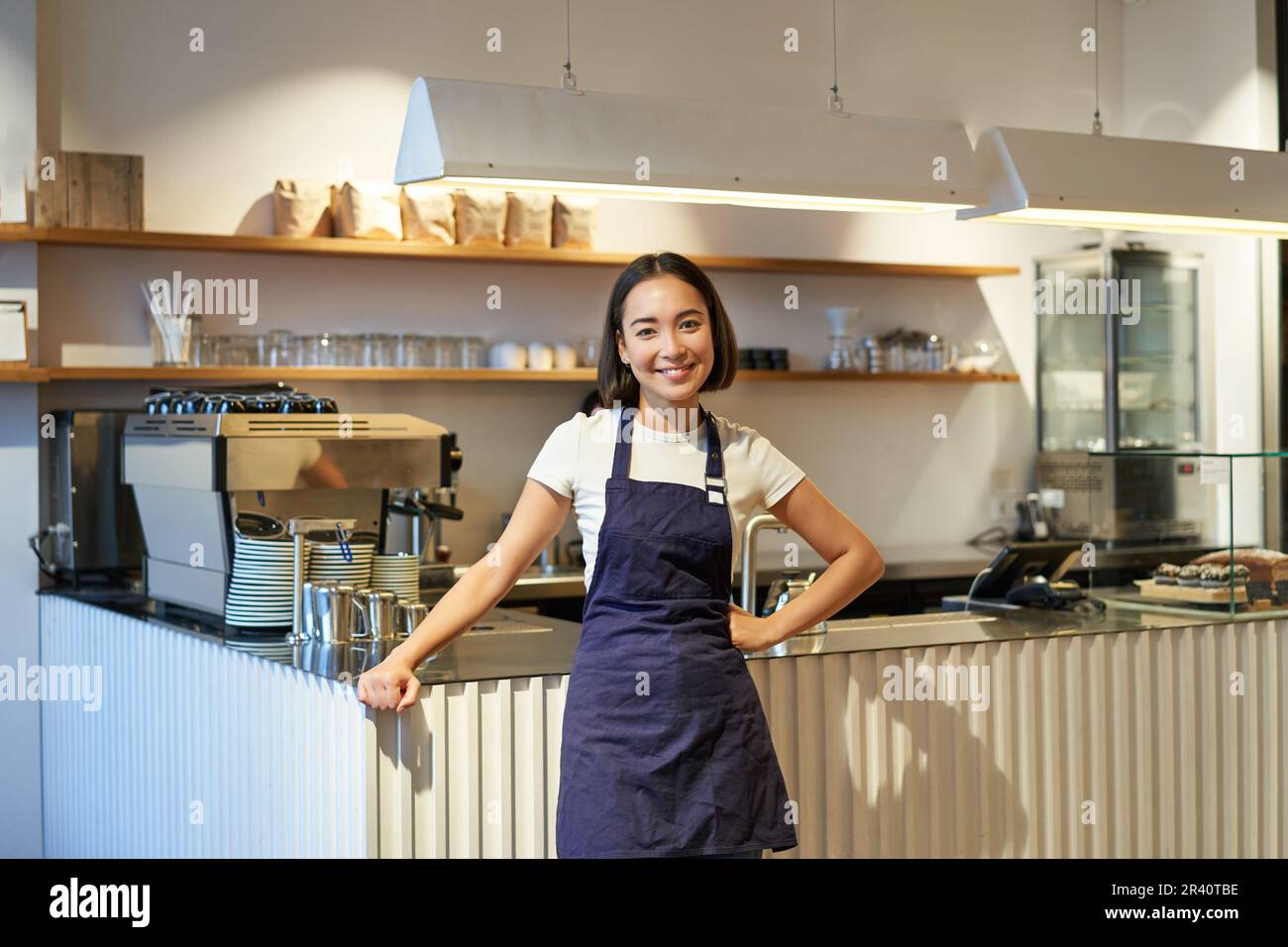 Portrait of cute asian woman barista, cafe staff standing near counter ...