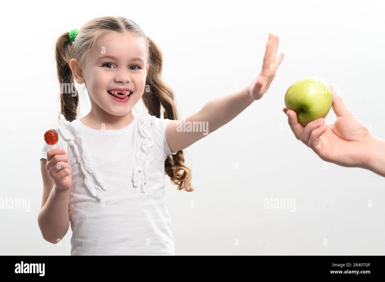 Little girl chooses a lollipop over an apple, sweets and fruits, choice ...