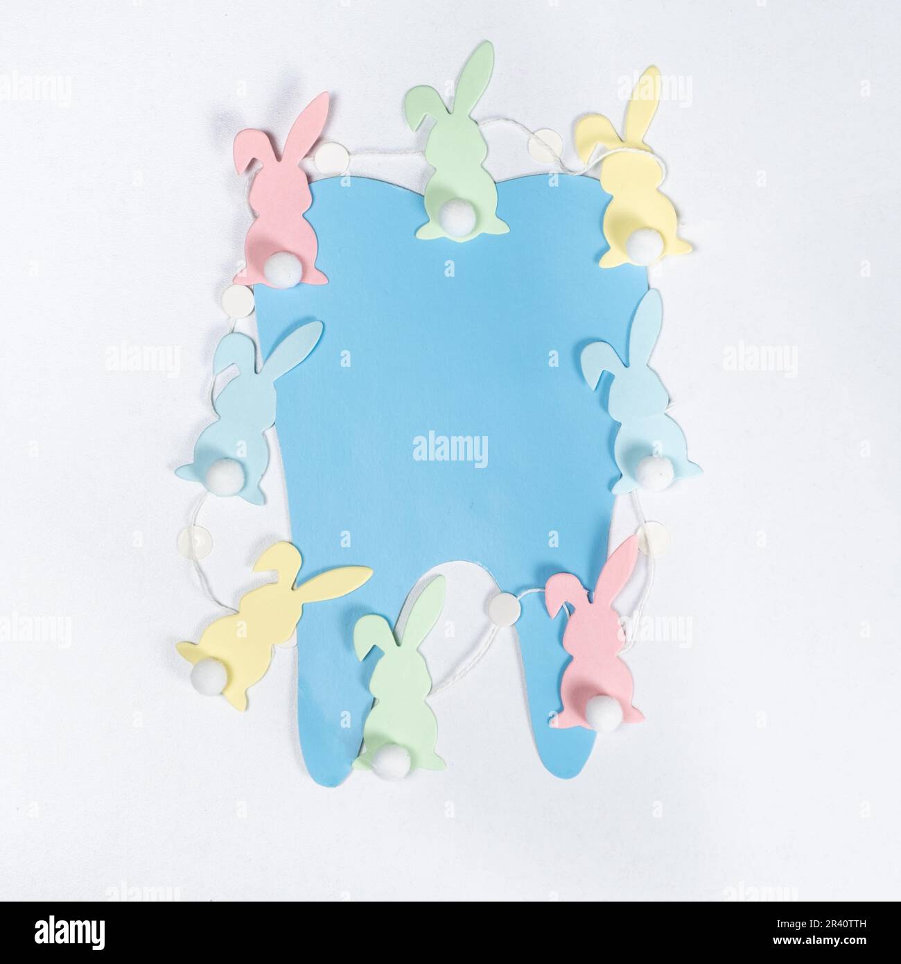 Easter dentistry. Blue tooth and garland of rabbits on a white ...